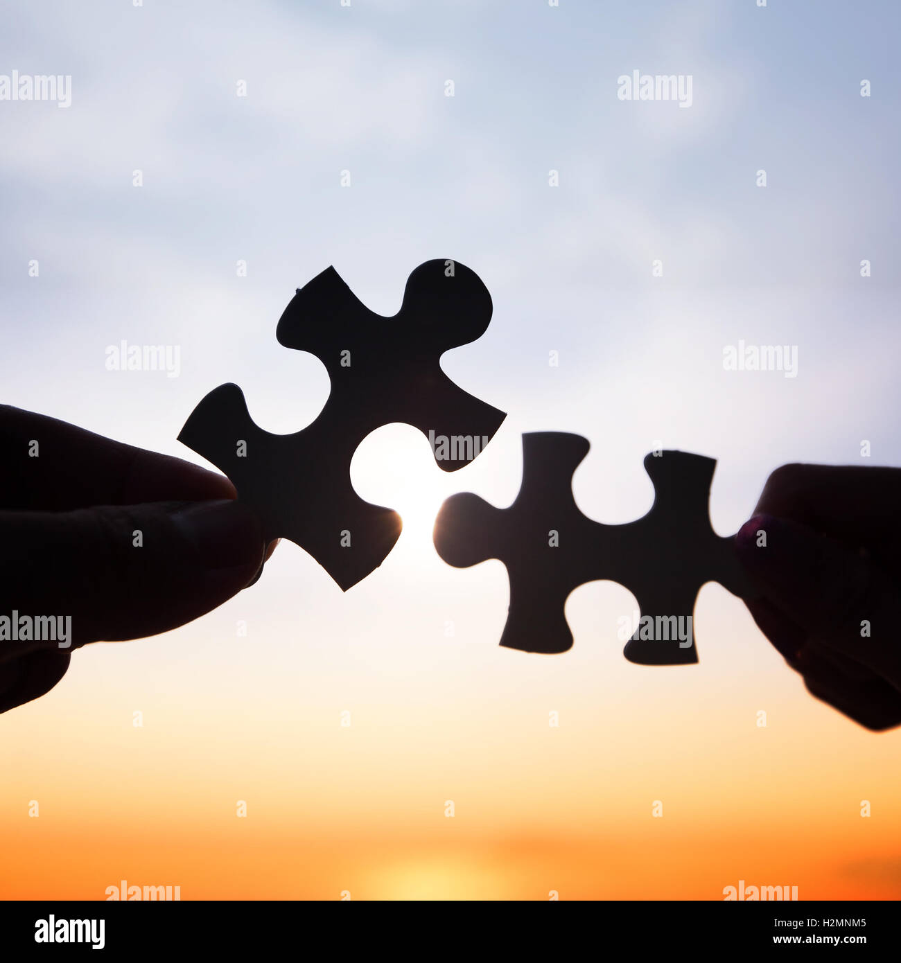 Two hands trying to connect puzzle pieces Stock Photo - Alamy