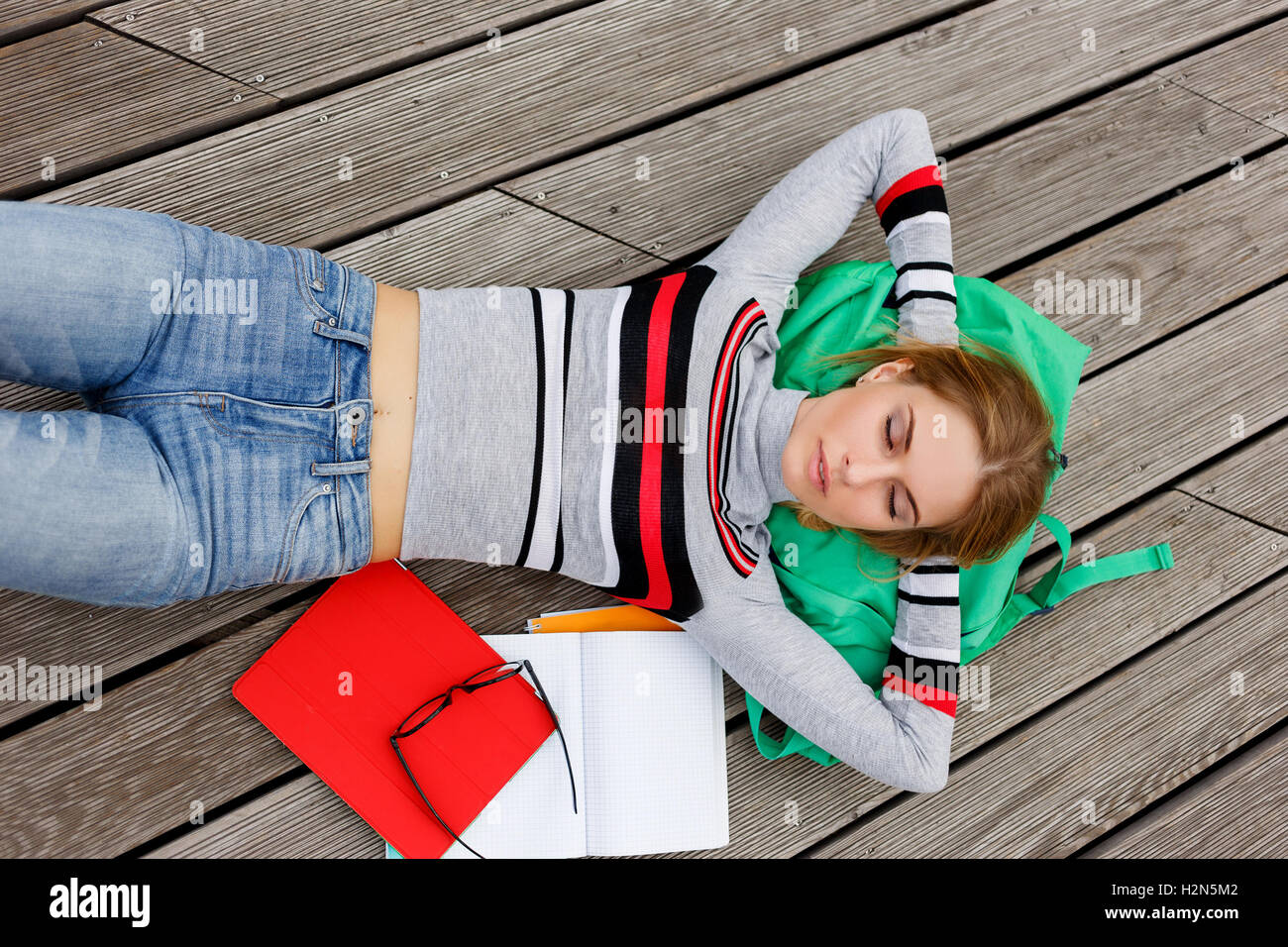 Student resting lying on wooden floor in street Stock Photo - Alamy