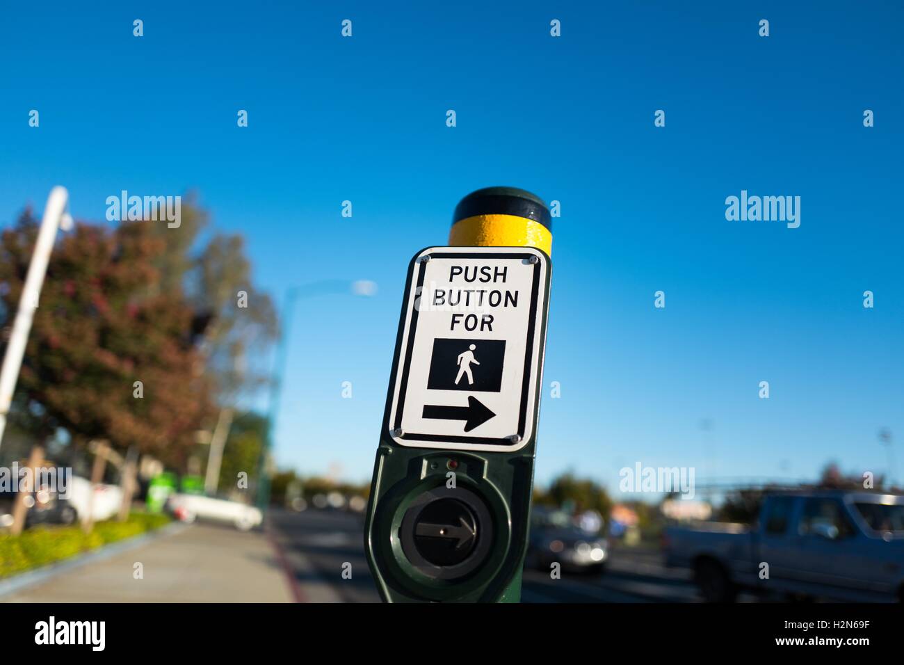 A button on a pedestal, with a sign indicating that pedestrians should ...
