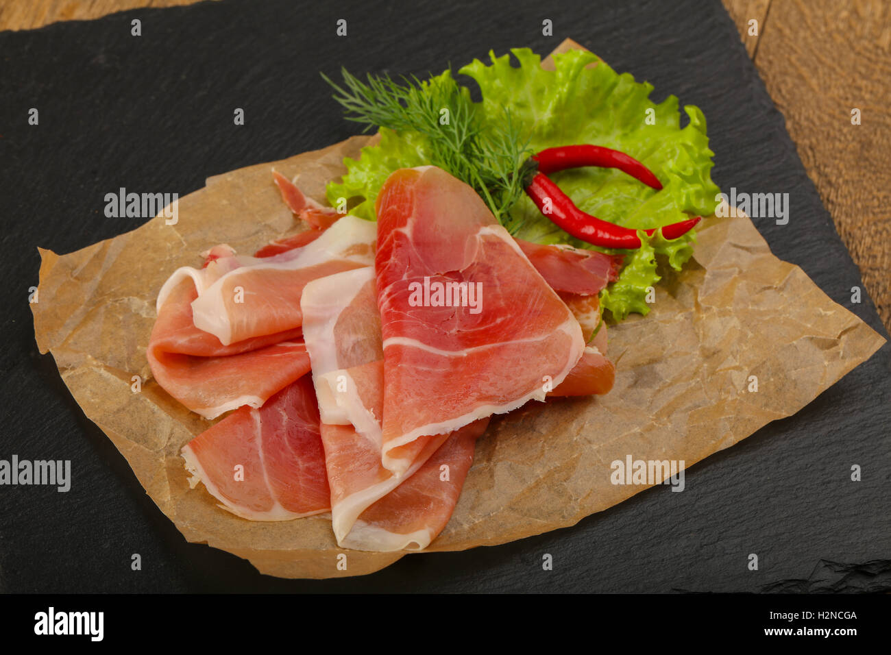 Ham serrano with salad leaves on wood background Stock Photo - Alamy