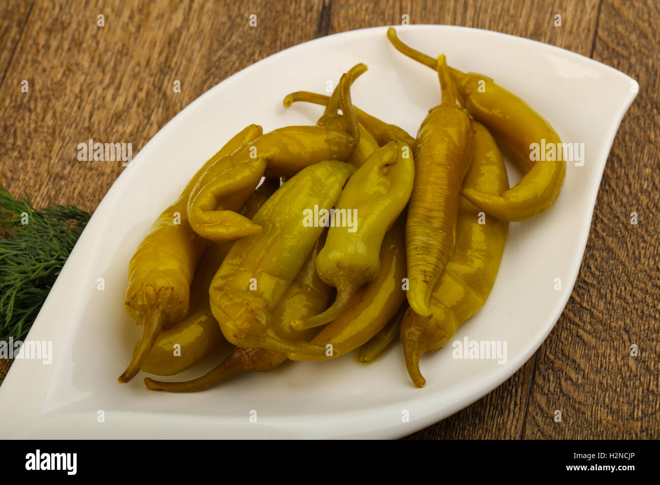 Pickled green pepperoni pepper in the bowl on wood background Stock ...
