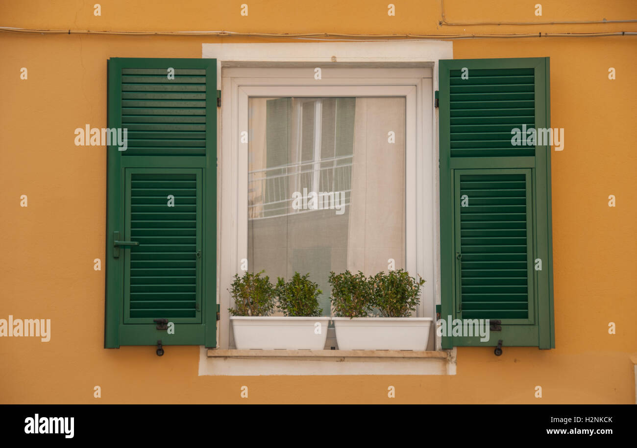 A brightly coloured building showing its window detail and shutters ...