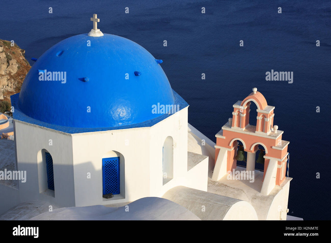Traditional Greek white church arch with cross and bells in village Oia ...