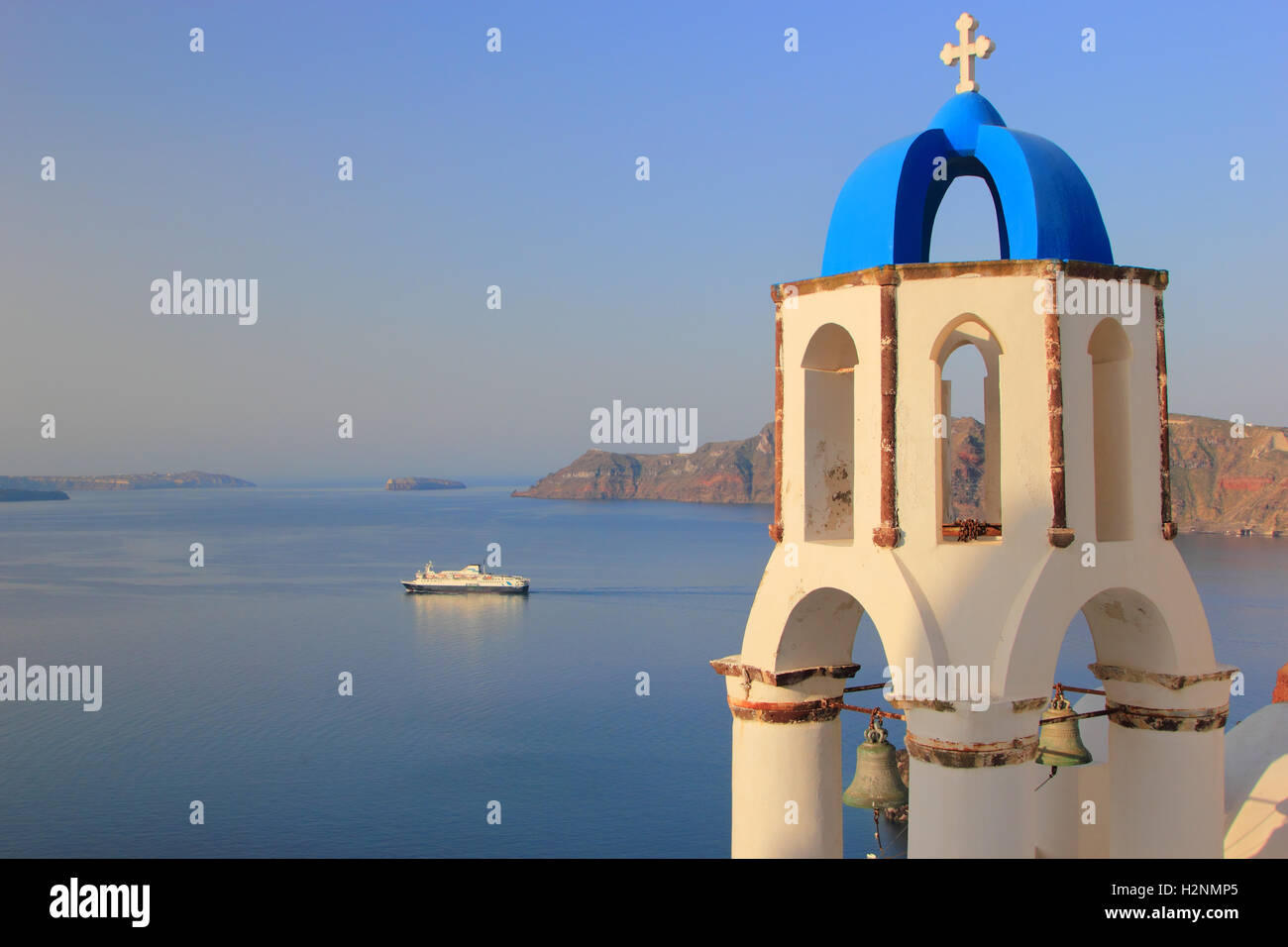 Traditional Greek white church arch with cross and bells in village Oia ...