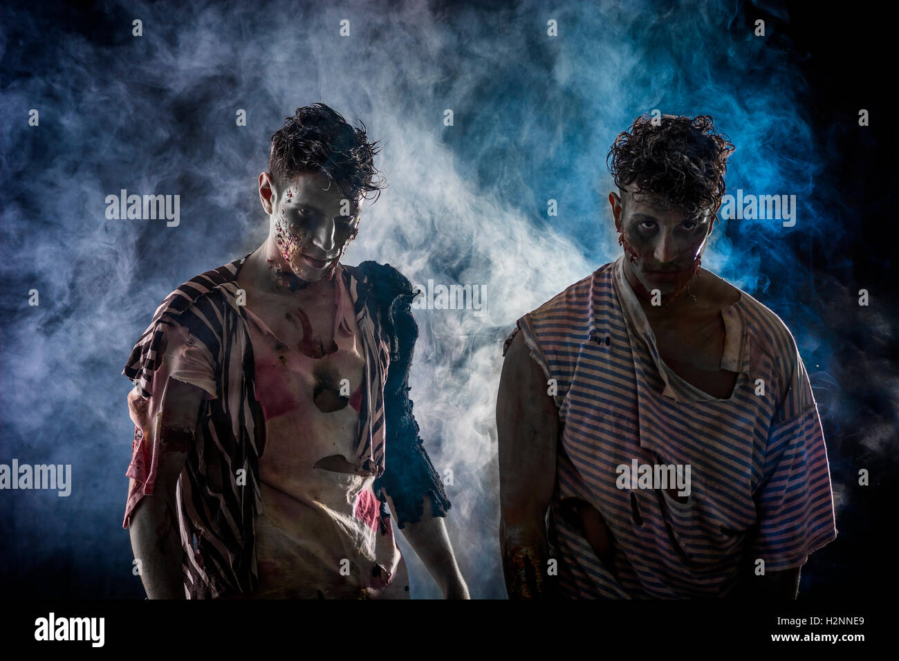 Two male zombies standing on black smoky background, head and shoulder ...