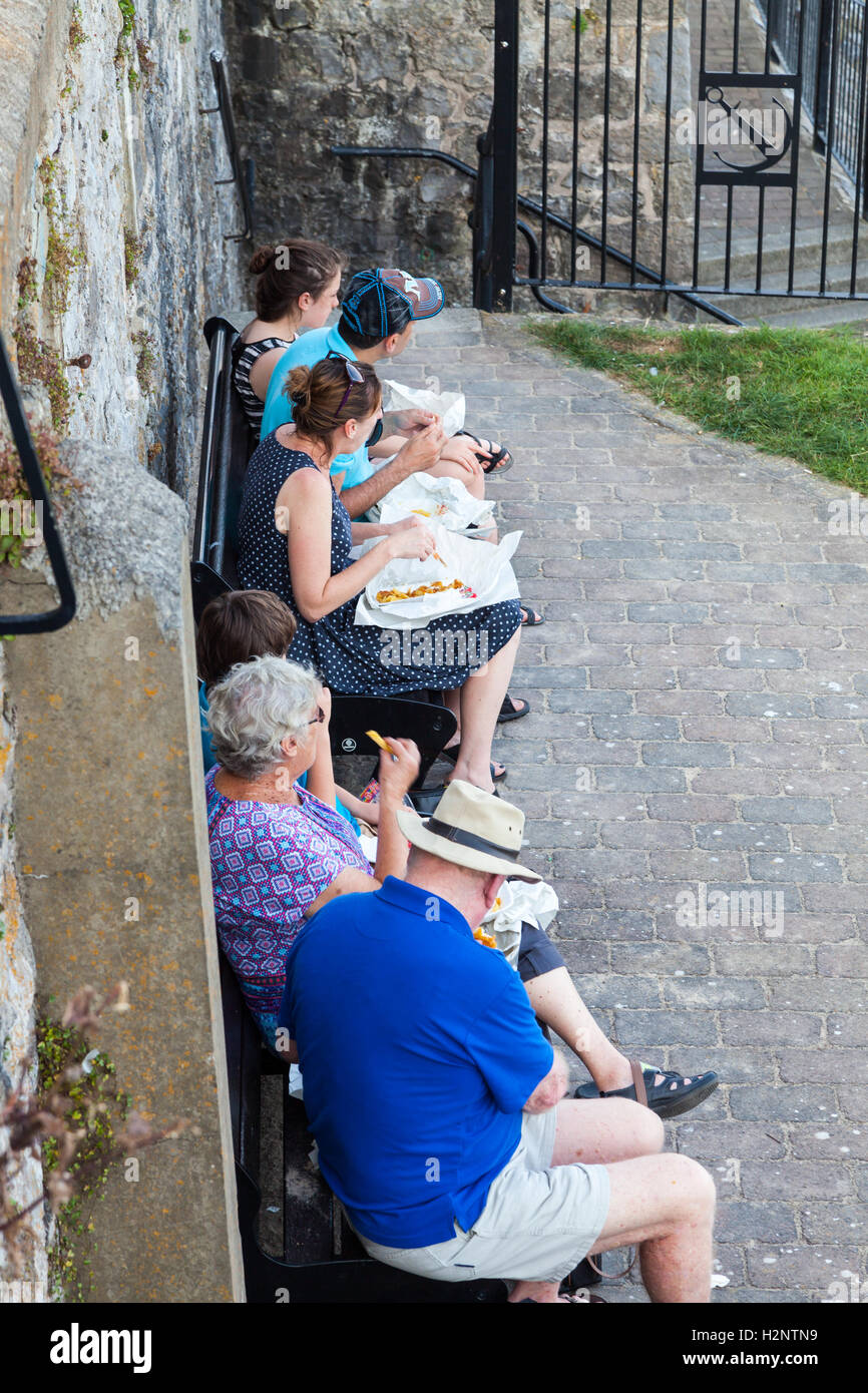 People eating chips at Tenby front Stock Photo - Alamy
