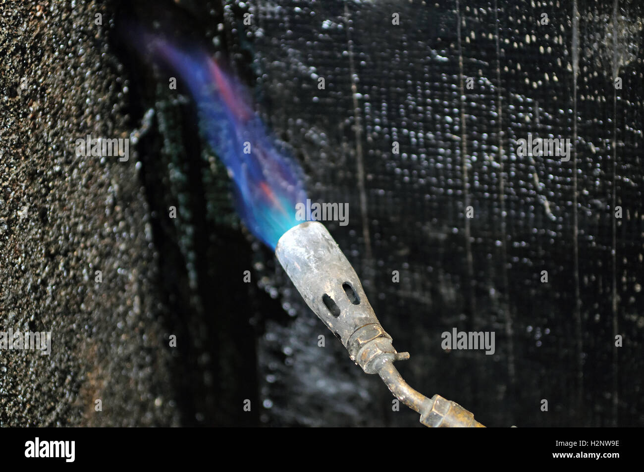 Bituminous waterproofing membrane is being welded with butane torch ...