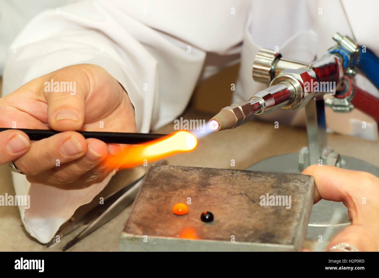 Artist shaping hot glass using a gas flame Stock Photo - Alamy