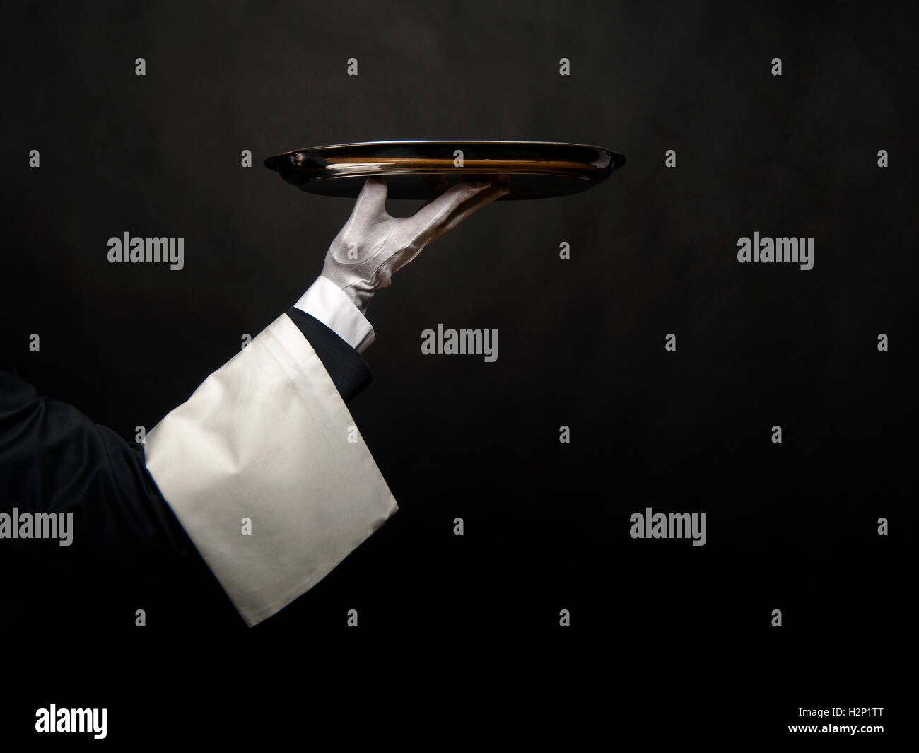 Waiter hand holding tray over black background Stock Photo - Alamy