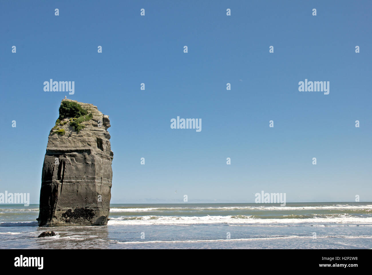 A lone rock towers above the beach in North Taranaki, New Zealand Stock ...