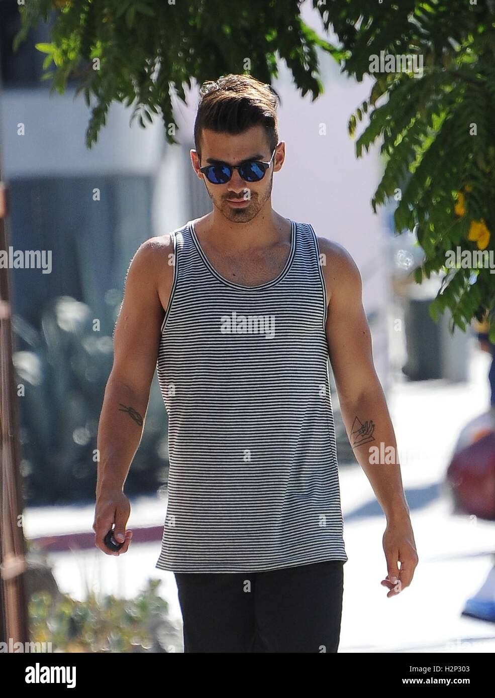 Joe Jonas wears a striped tank revealing his tattoos while out with a ...