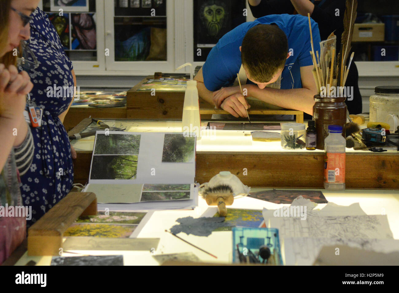 A design student works hard on cutting a shape,, tracing it as it lays ...