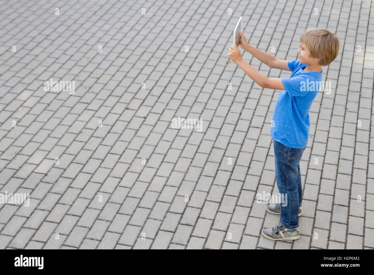 Boy using mobile phone. Child taking photo with his smartphone. Gray ...