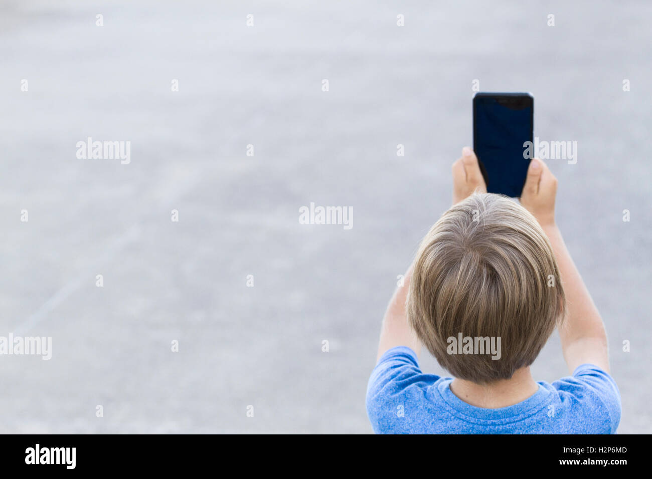 Boy using mobile phone. Child taking photo with his smartphone. Gray ...