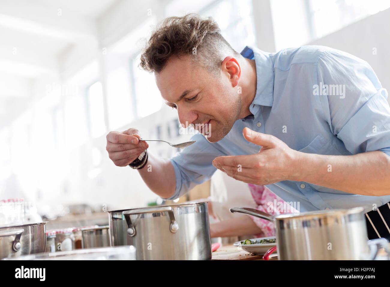 Man smelling food leaning over pot in cooking class kitchen Stock Photo ...