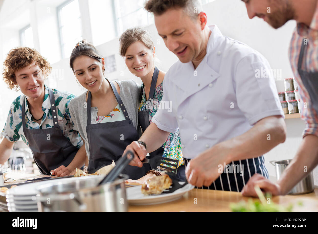 Students watching chef teacher in cooking class kitchen Stock Photo - Alamy