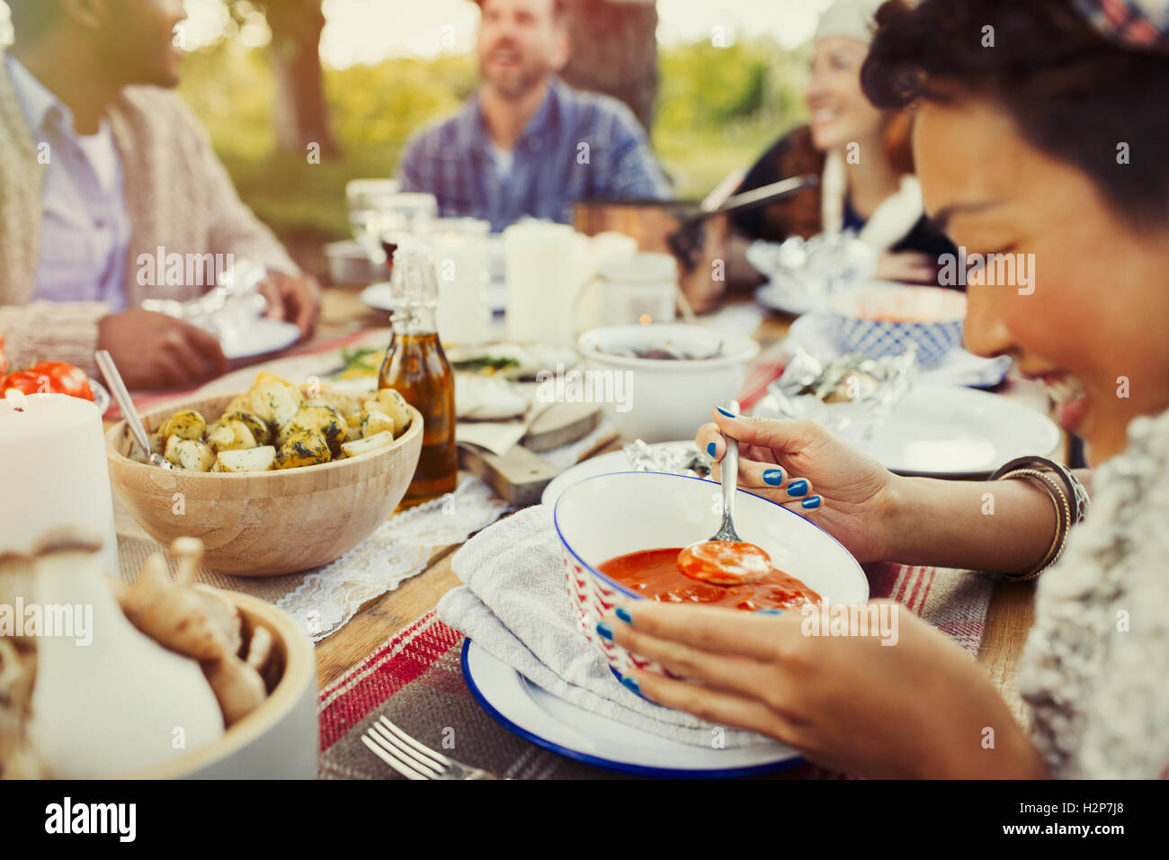 Smiling woman eating soup at patio table with friends Stock Photo - Alamy
