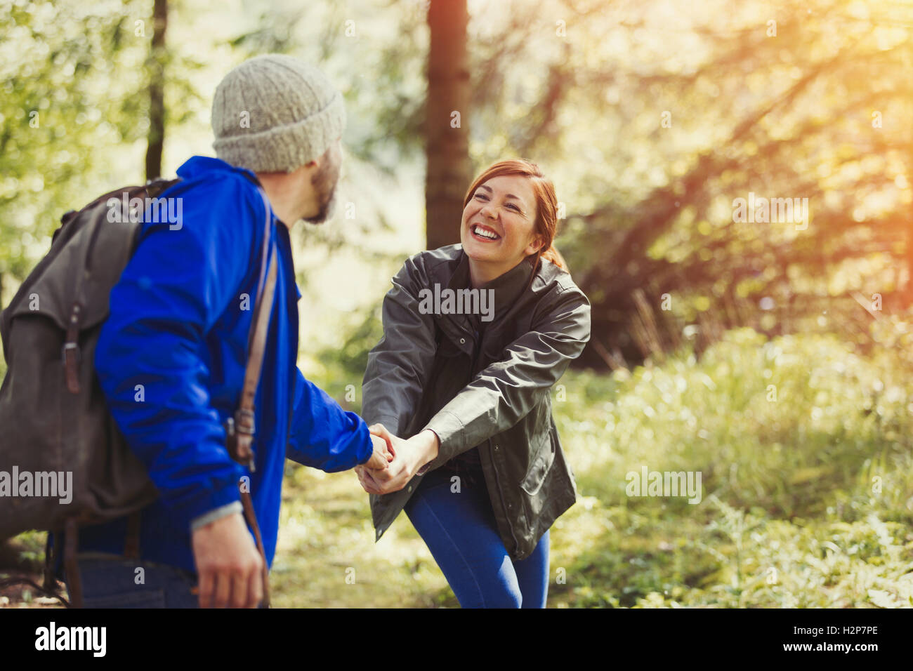 Smiling couple holding hands hiking in woods Stock Photo - Alamy