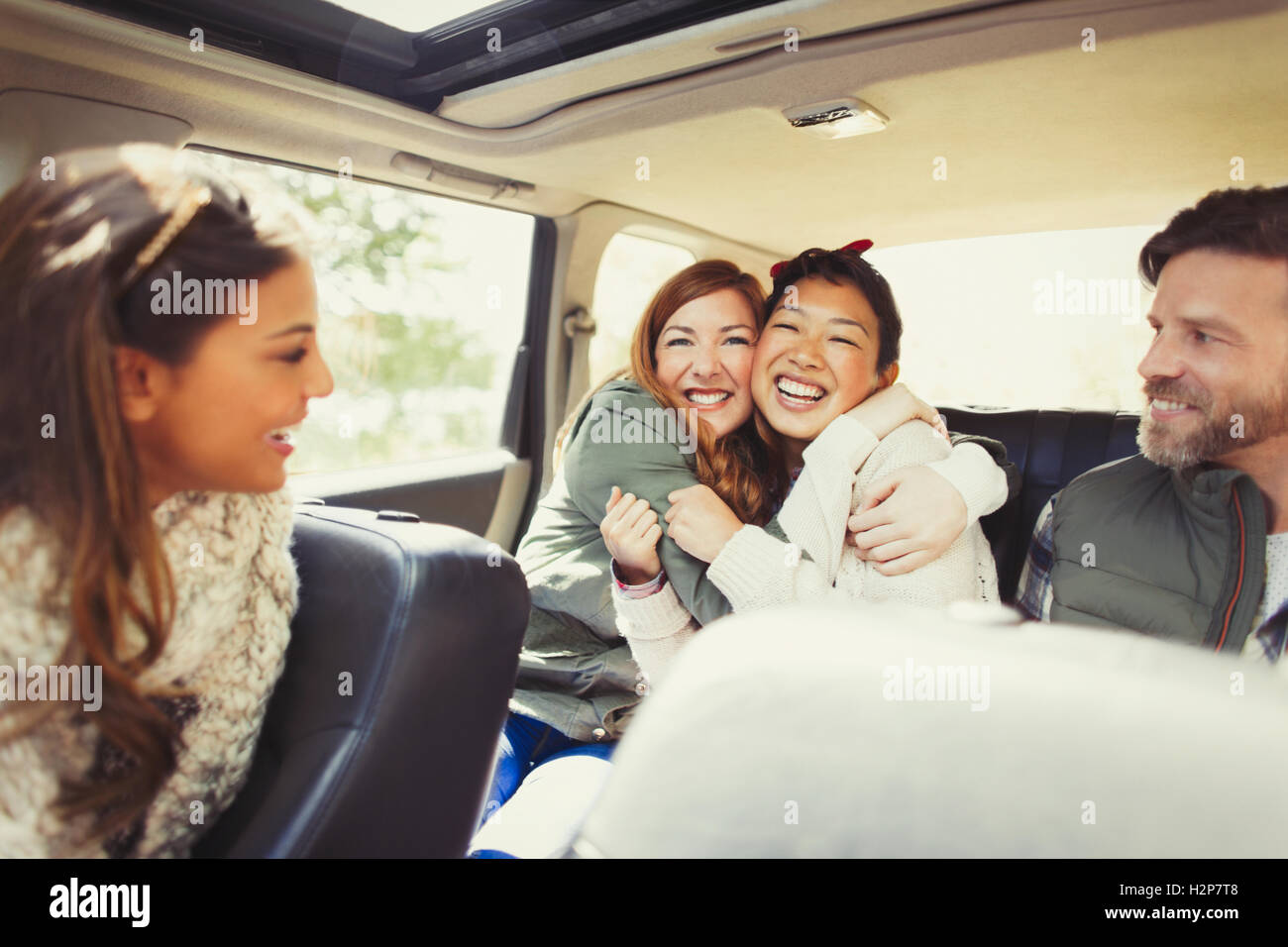 Enthusiastic female friends hugging in back seat of car Stock Photo - Alamy