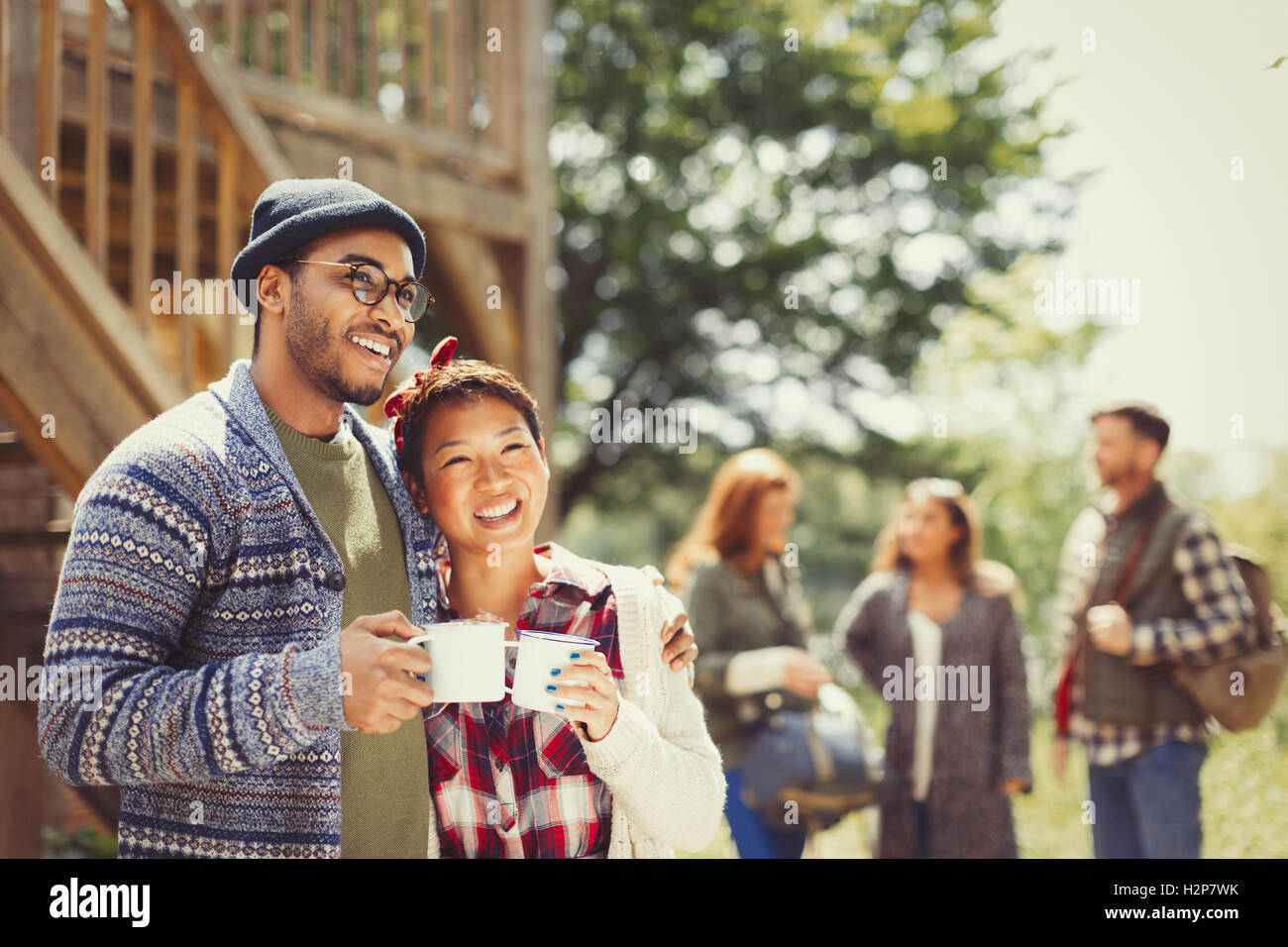 Smiling couple drinking coffee outside sunny cabin Stock Photo - Alamy