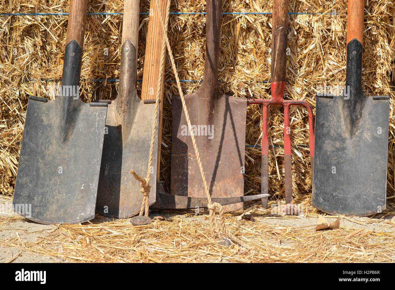 Farming and gardening tools displayed against hay bale Stock Photo - Alamy