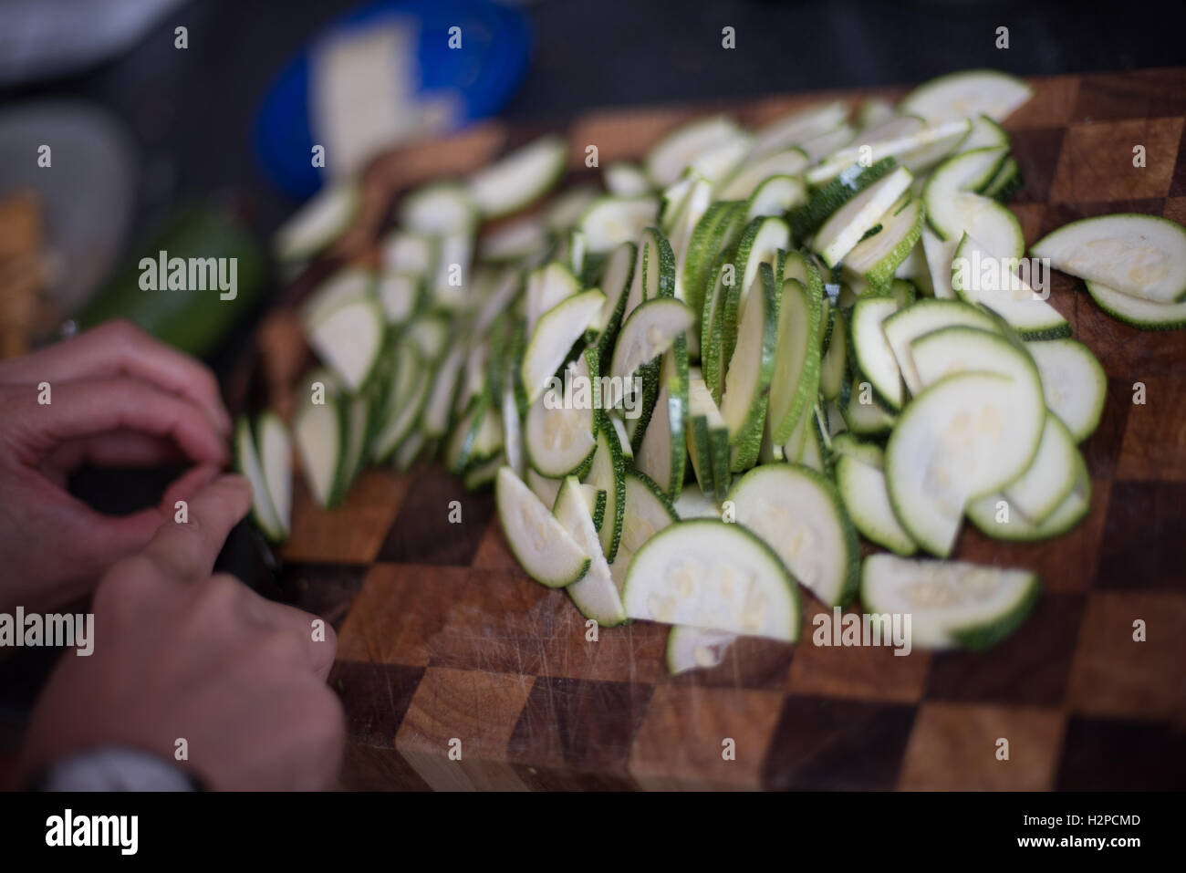 Person cutting zucchini courgette on a wooden board Stock Photo - Alamy