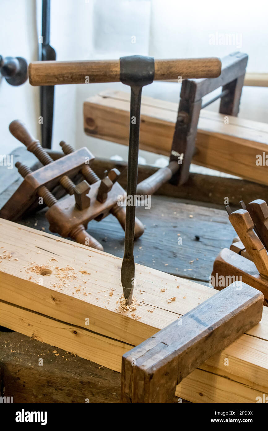 Auger stands in a wooden beam. Old carpentry workshop with obsolete ...