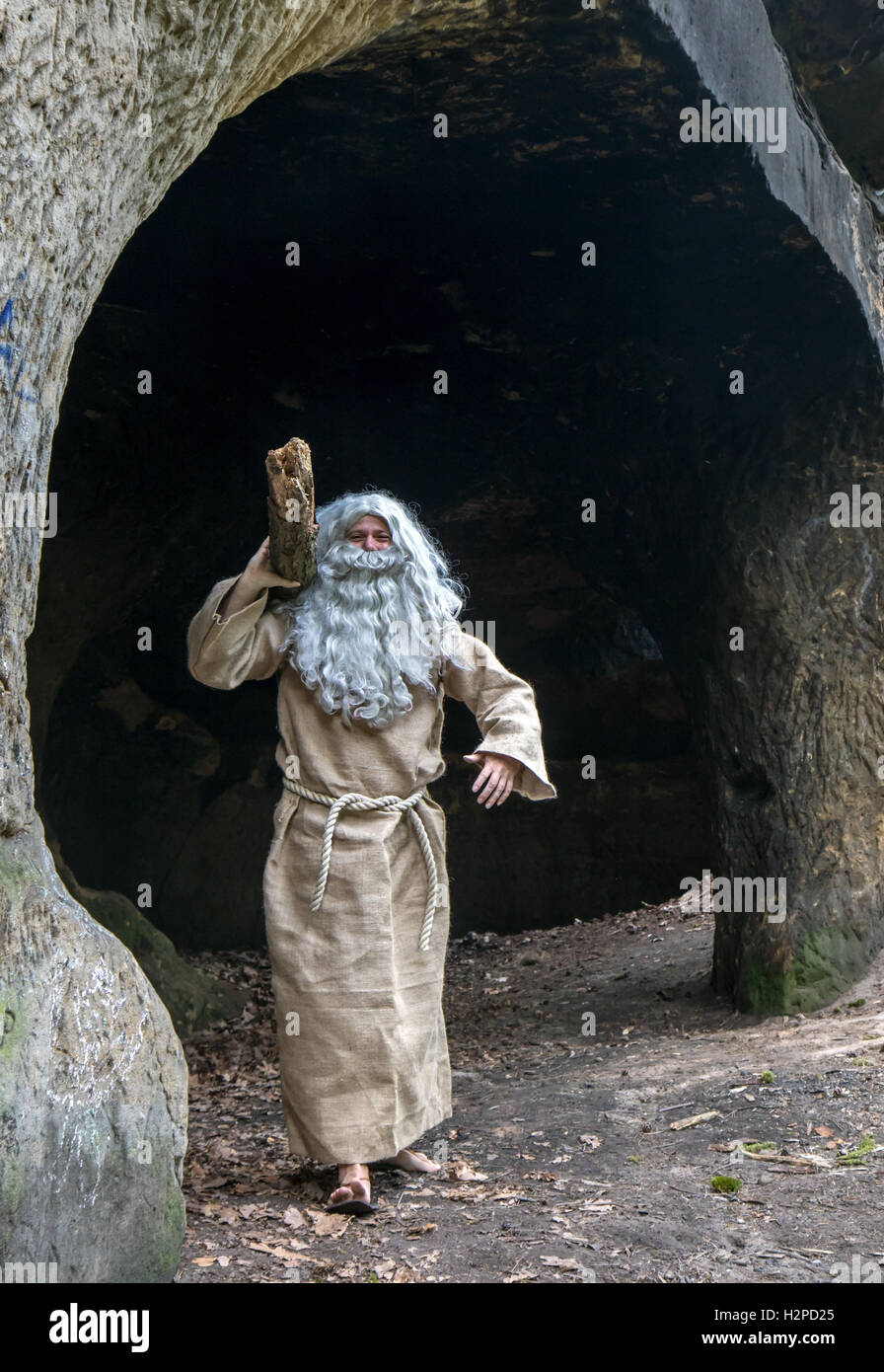 The bearded monk carries log. The old hermit working in a cave Stock ...