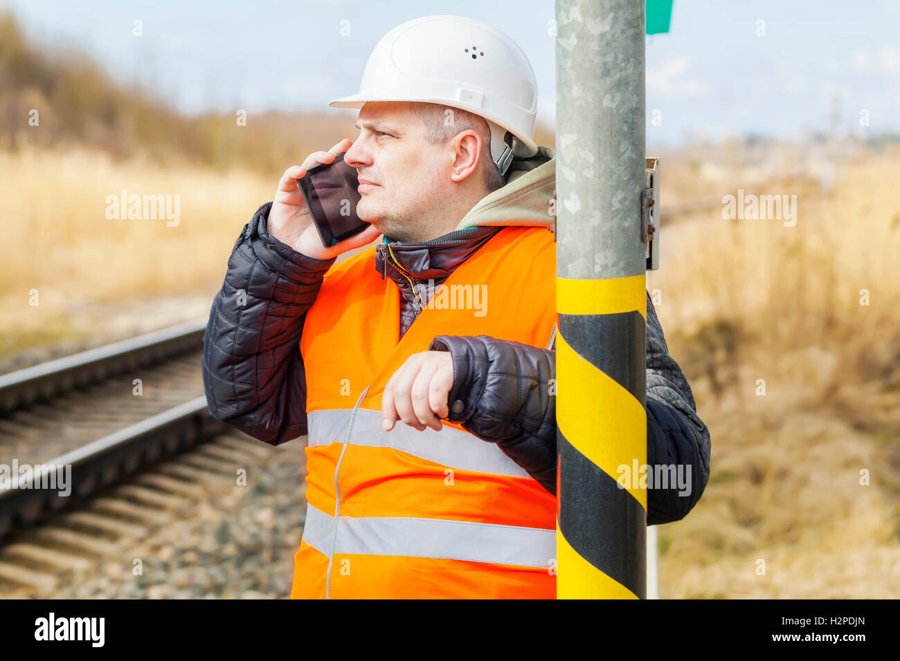Railway employee talking on cell phone near railway Stock Photo - Alamy
