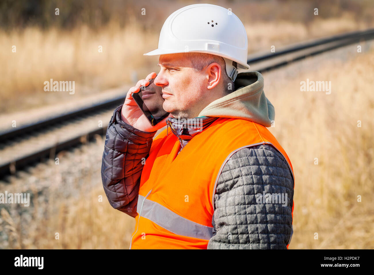 Railway employee talking on cell phone near railway Stock Photo - Alamy