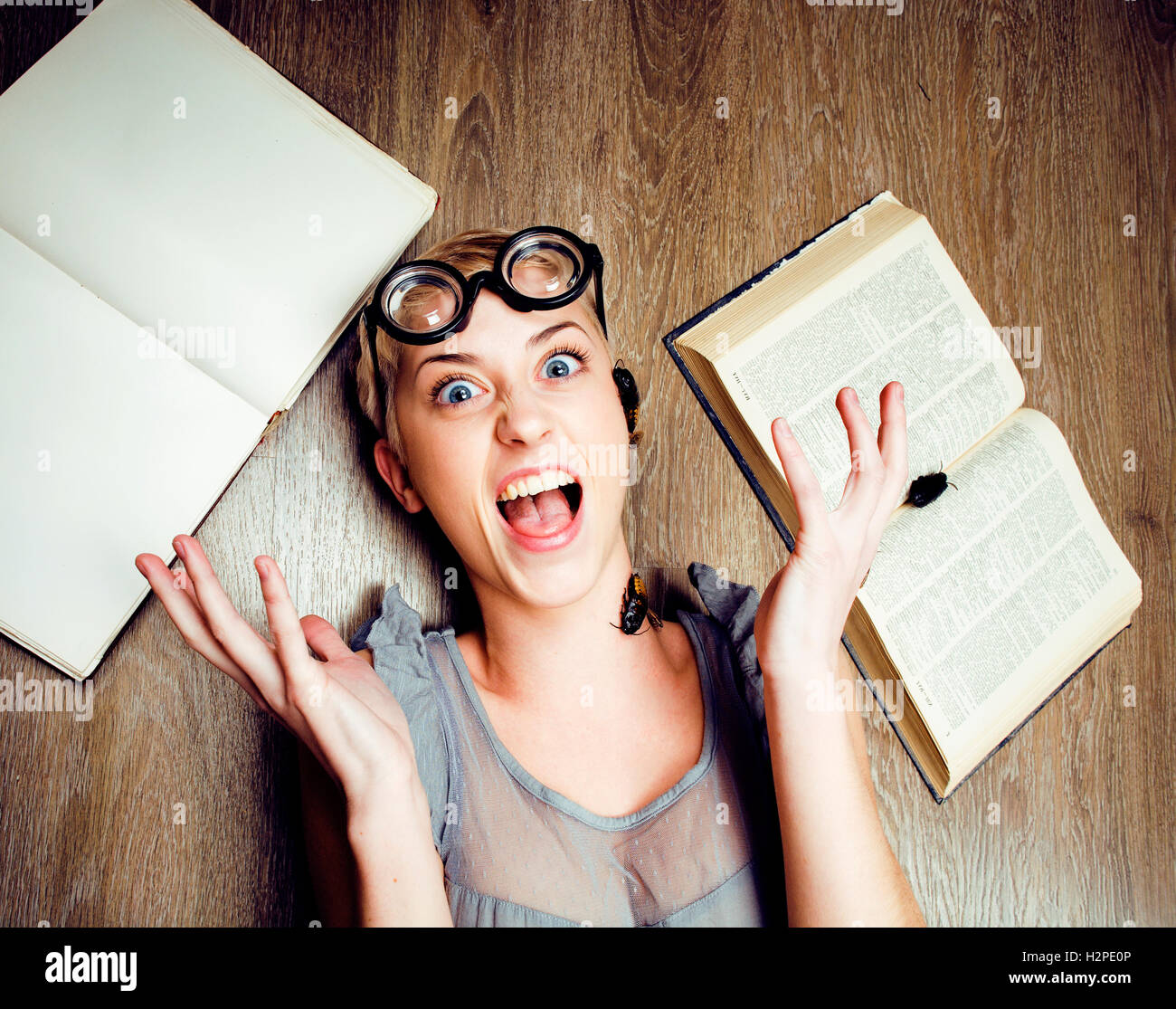portrait of crazy student girl in glasses with books and cockroaches ...