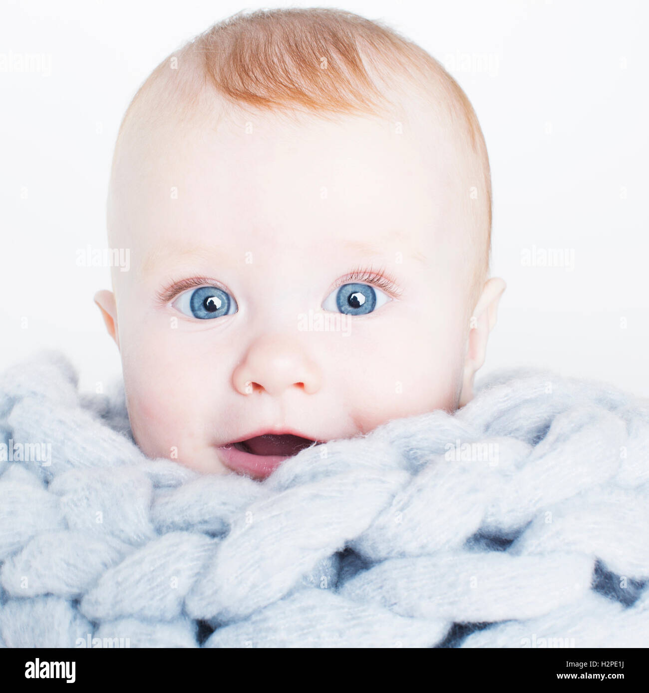 little cute red head baby in scarf all over him close up isolated ...