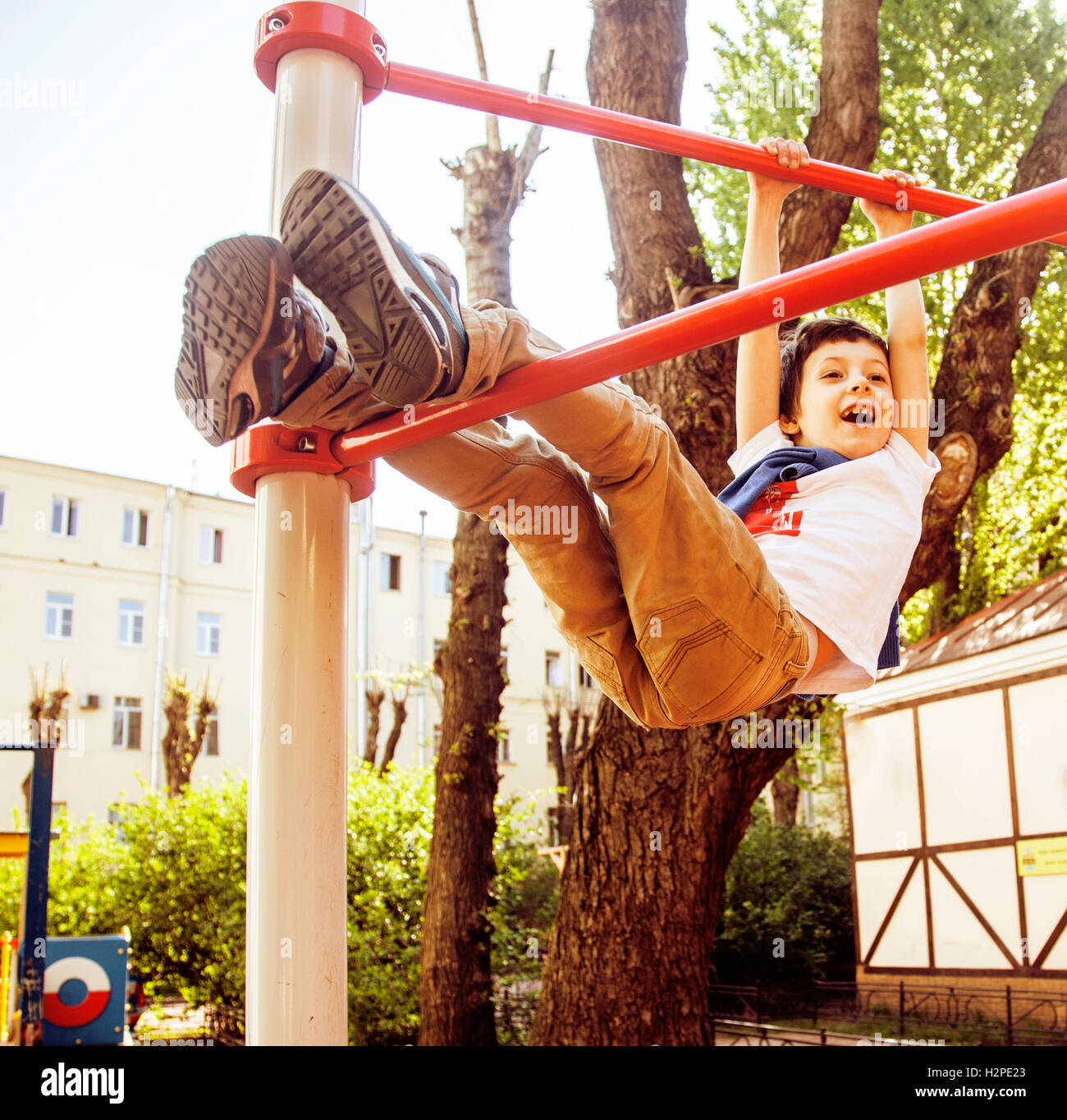 little cute blond boy hanging on playground outside, alone training ...
