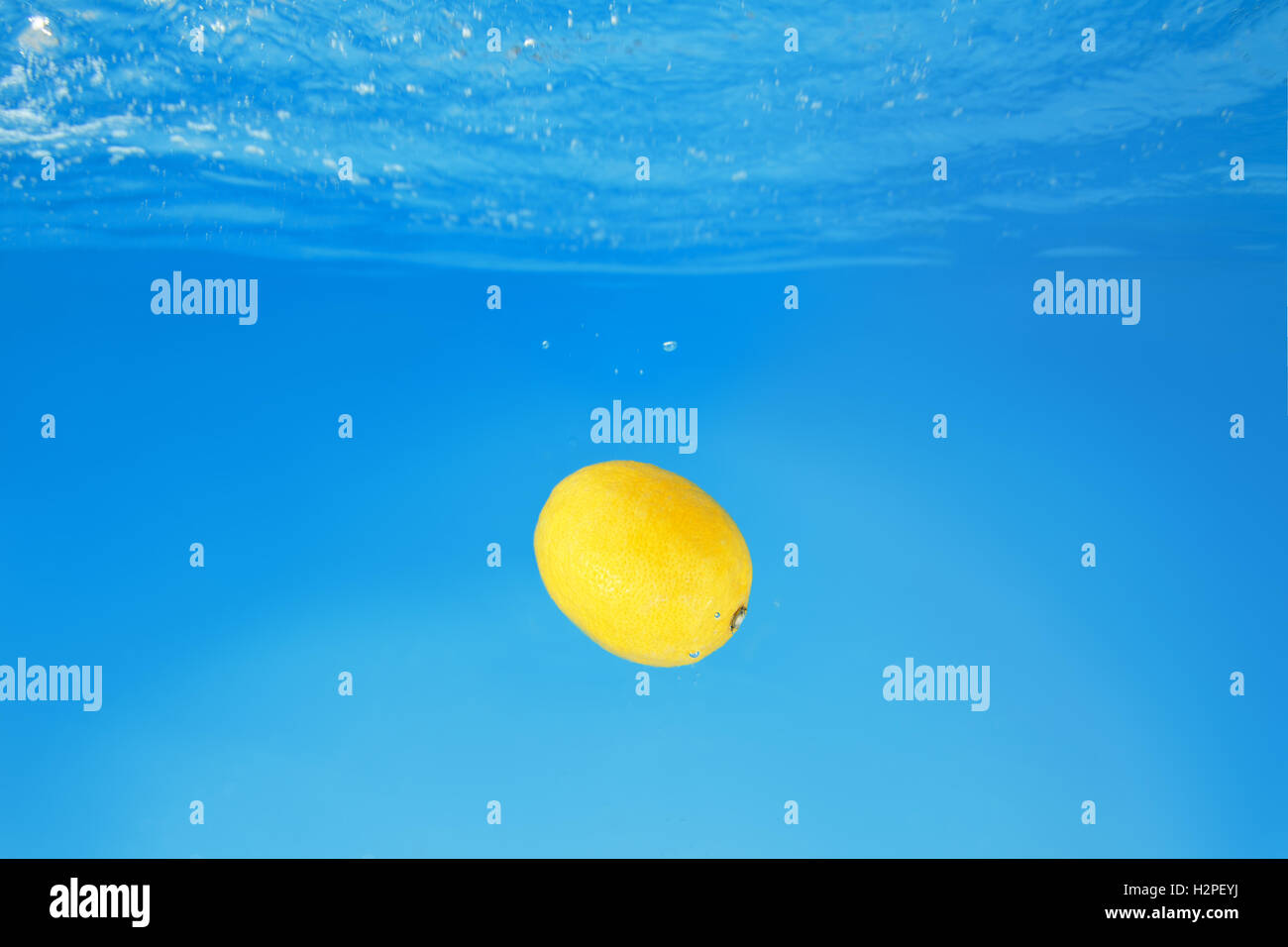 Lemon splashing in blue water Stock Photo - Alamy