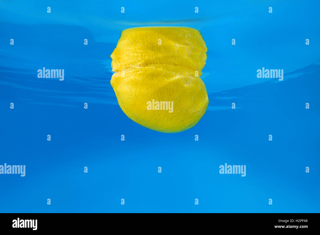 Lemon splashing in blue water Stock Photo - Alamy
