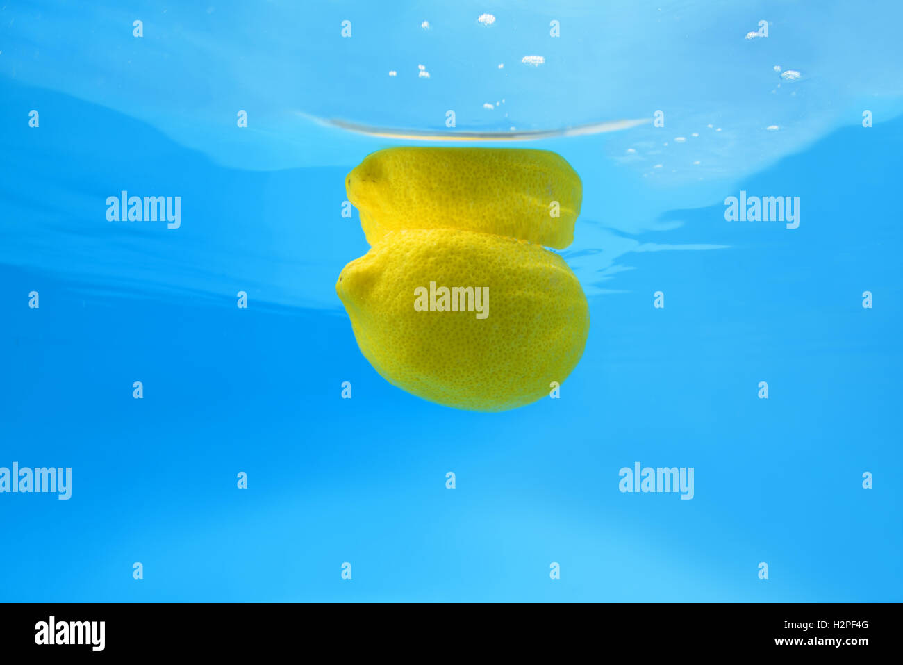 Lemon splashing in blue water Stock Photo - Alamy