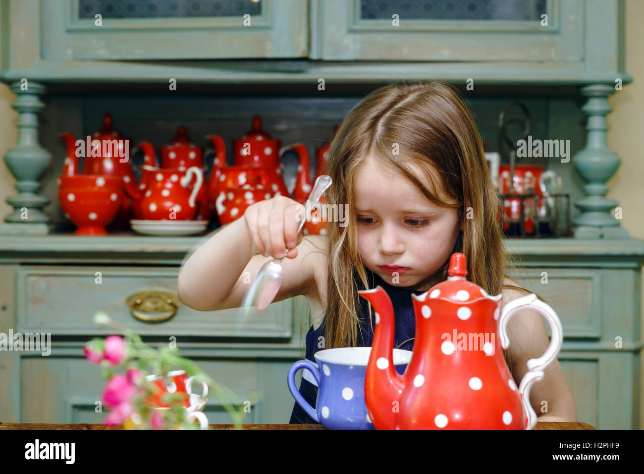 Cute little girl preparing tea in teapot on the kitchen, childhood ...