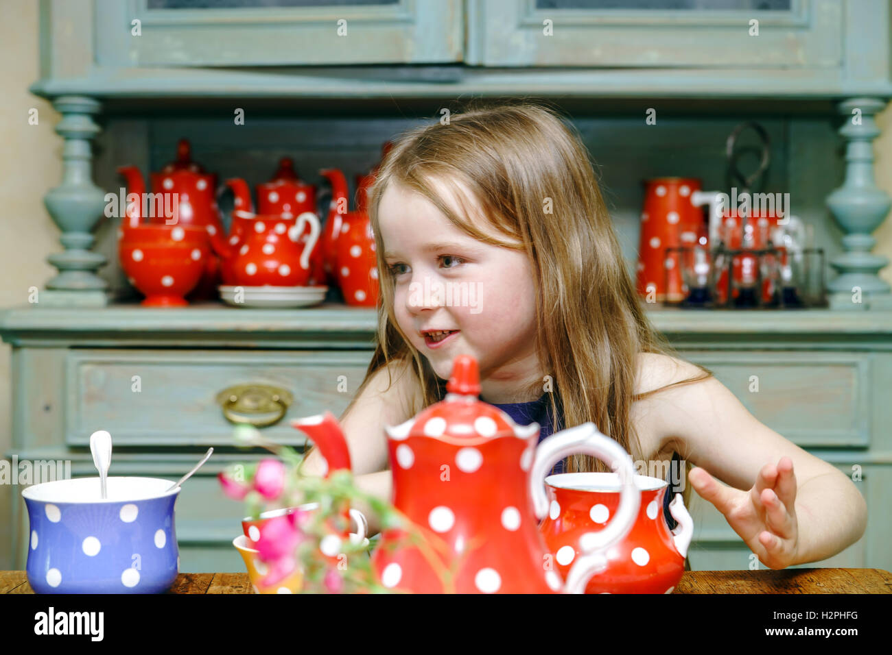 Cute little girl preparing tea in teapot on the kitchen, childhood ...