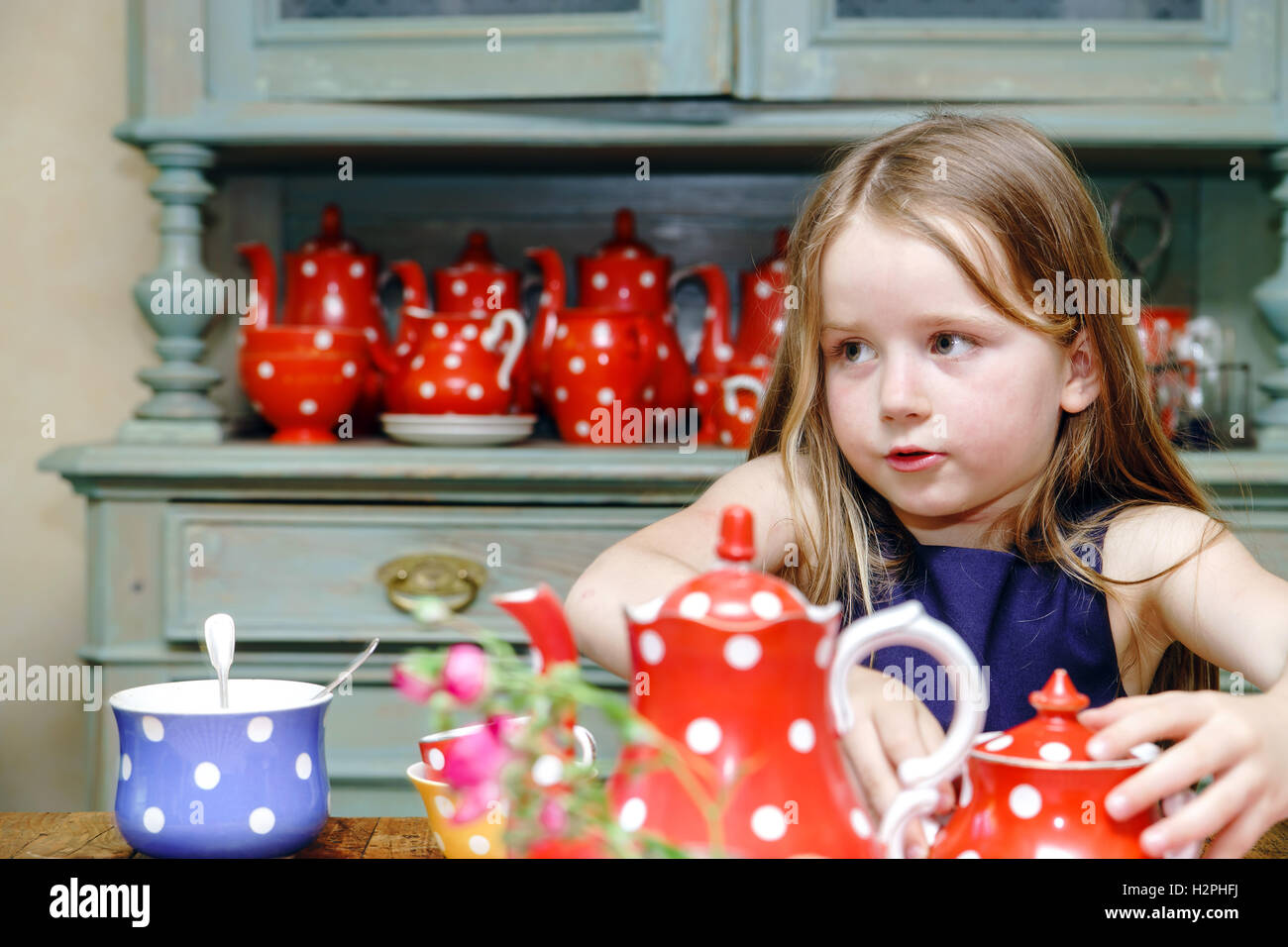 Cute little girl preparing tea in teapot on the kitchen, childhood ...