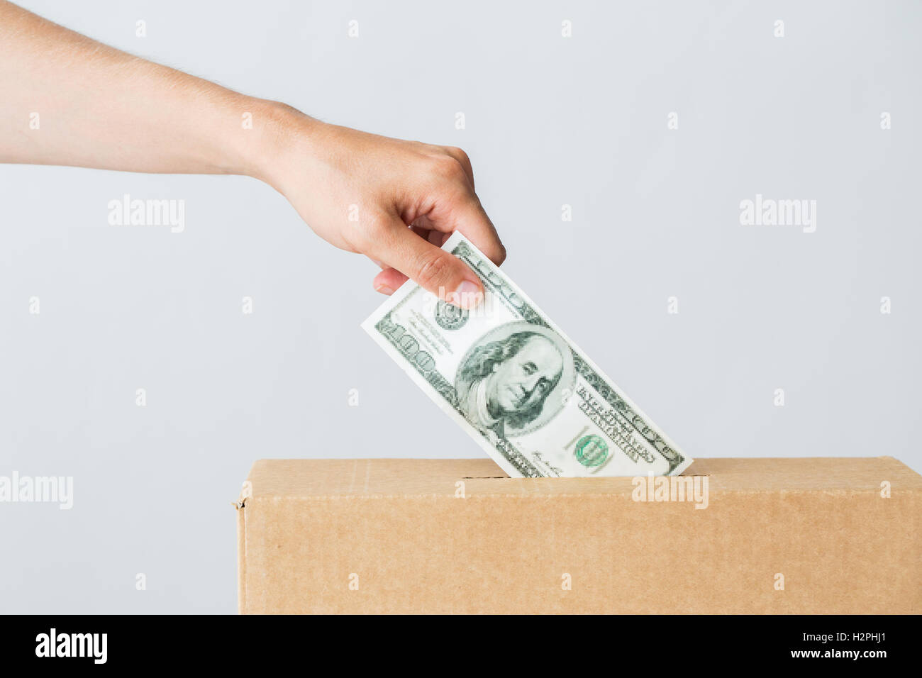 man putting dollar money into donation box Stock Photo - Alamy