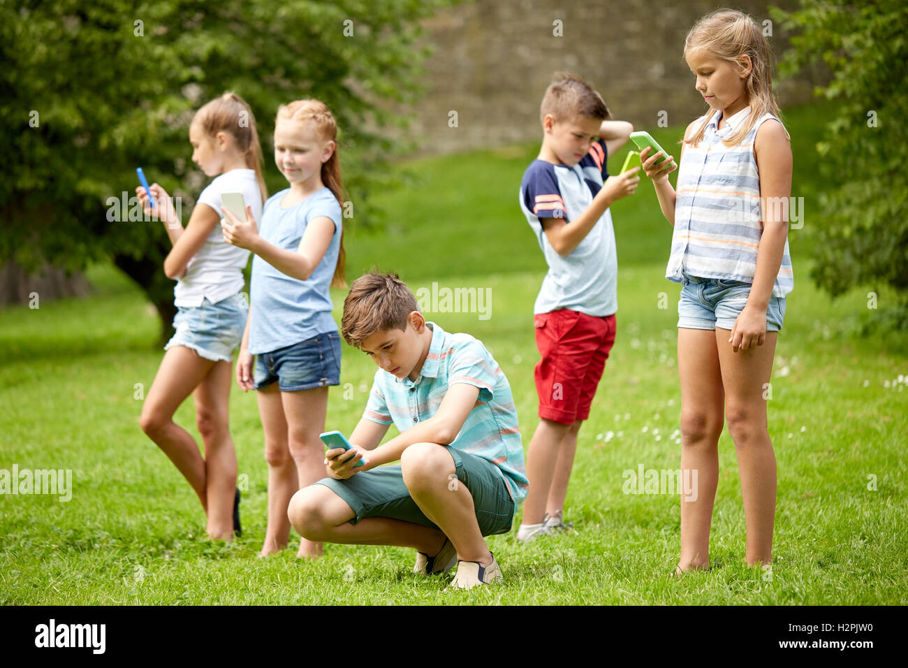kids with smartphones playing game in summer park Stock Photo - Alamy