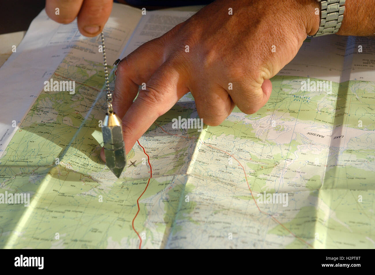 Search on a map with the help of a pendulum Stock Photo - Alamy