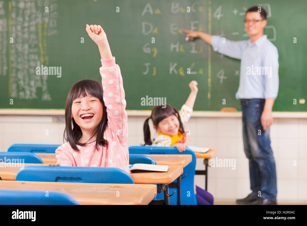asian pupils raising hands during the lesson Stock Photo - Alamy