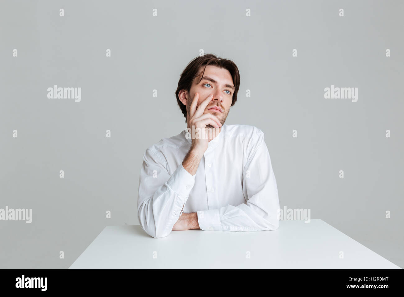 Thoughtful young man thinking about something while sitting at the ...