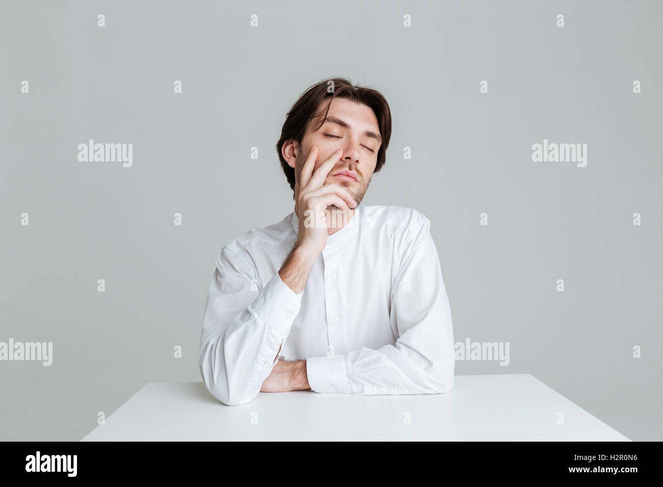 Thoughtful young man with eyes closed thinking about something while ...