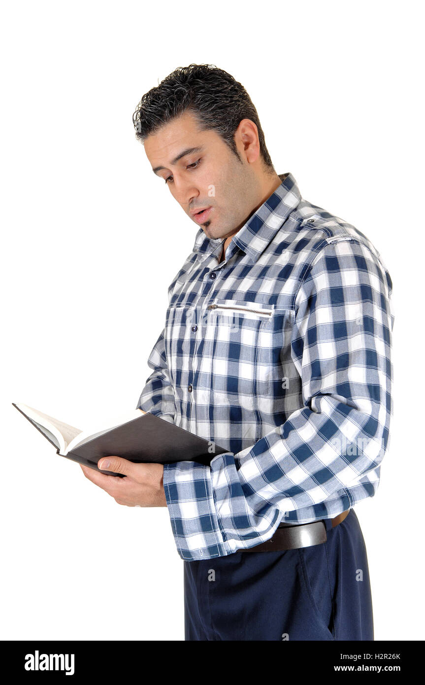 A young tall man standing for white background very relaxed with a book ...