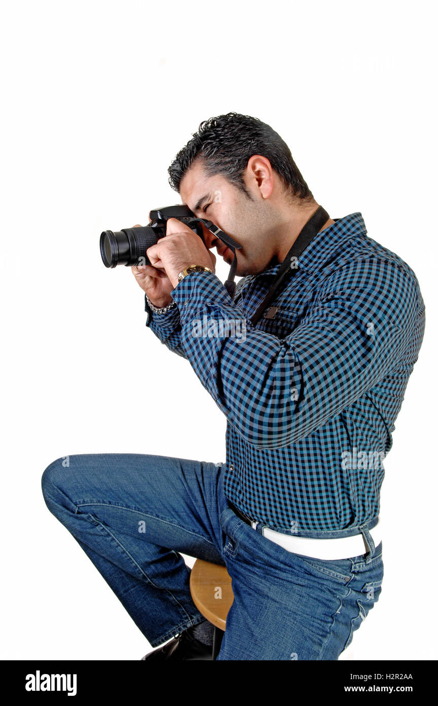 A young handsome man sitting on a chair taking pictures with his camera ...