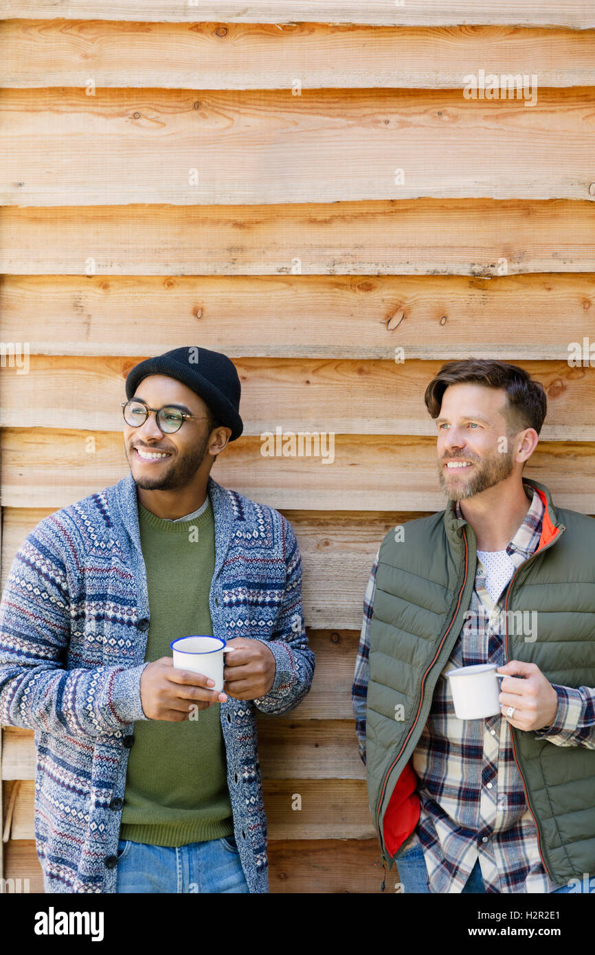 Smiling men drinking coffee outside cabin Stock Photo - Alamy
