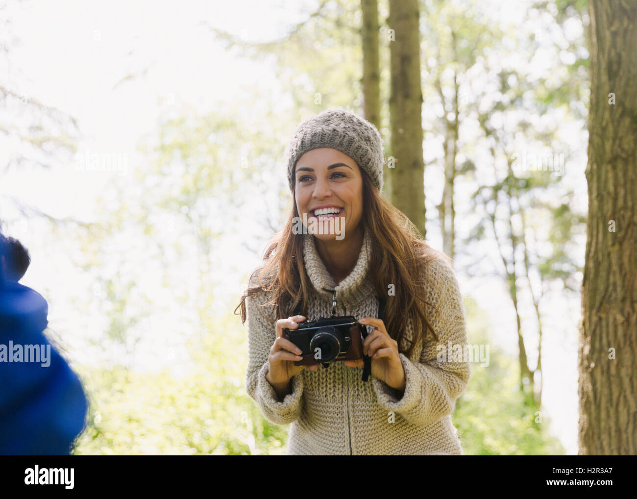 Smiling woman using camera in woods Stock Photo - Alamy