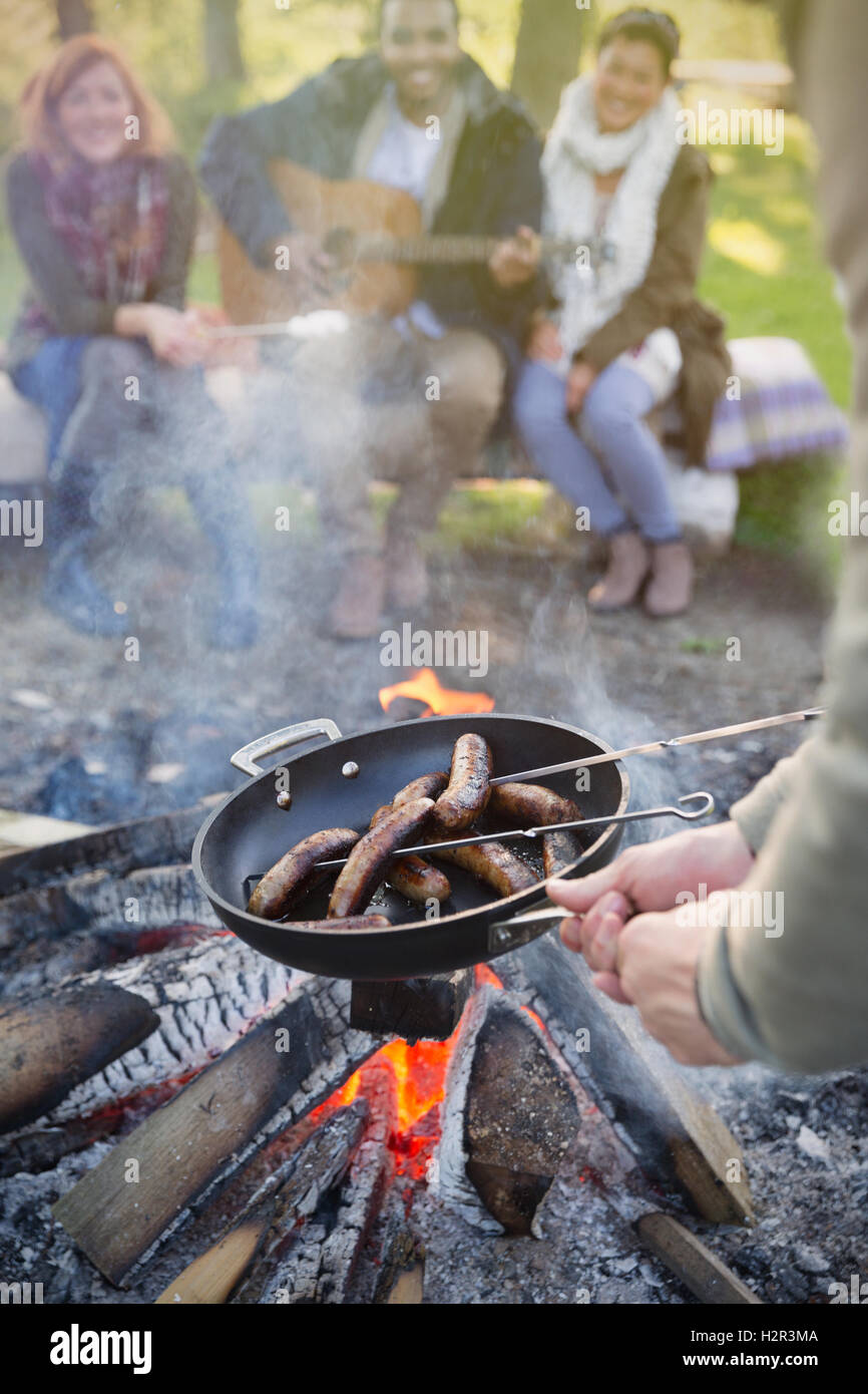 Friends cooking hot dogs over campfire Stock Photo - Alamy
